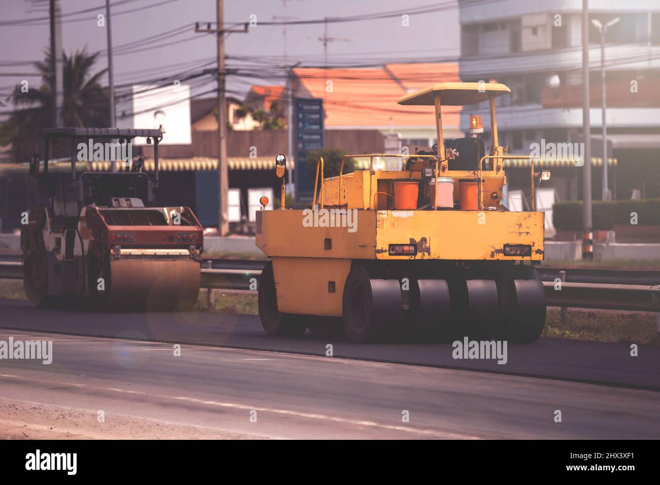 Workers, roller and operating asphalt paver machine during road ...