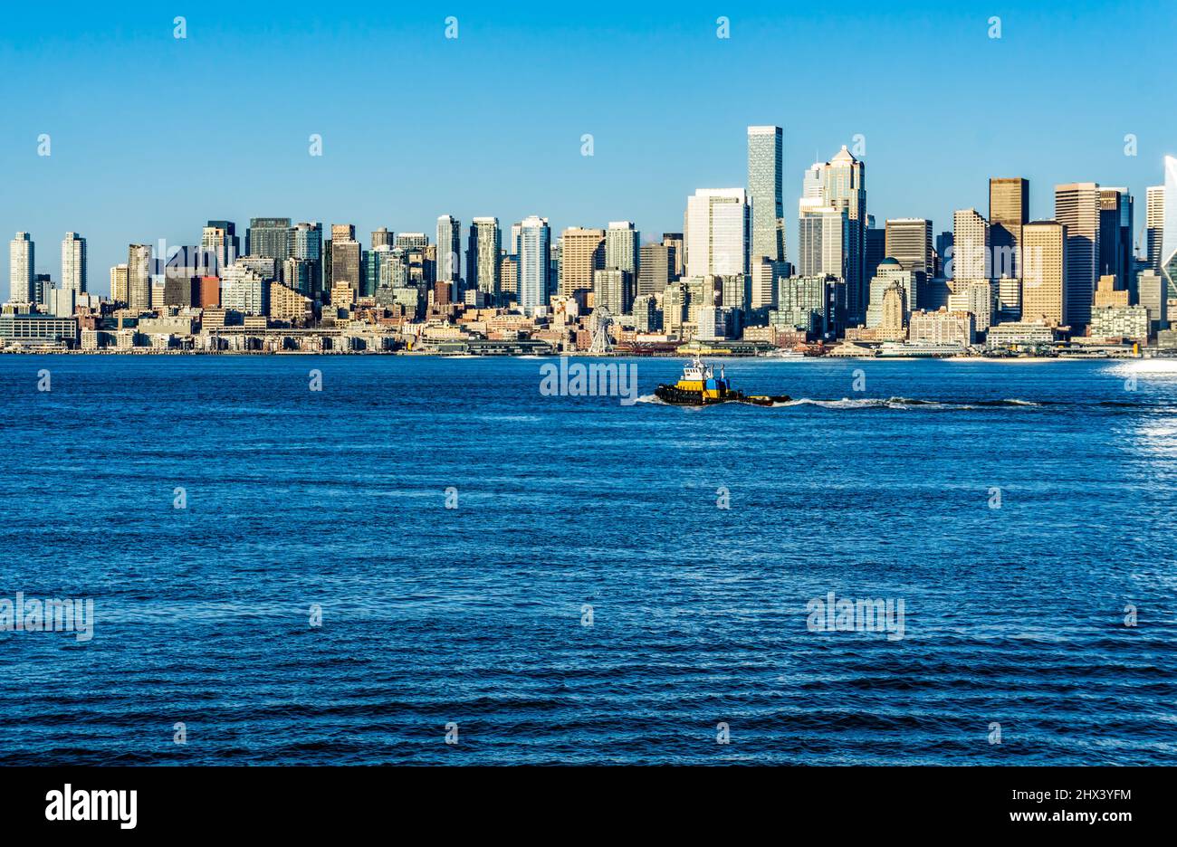 A tug boat moves across the Port of Seattle with the skyline in the ...