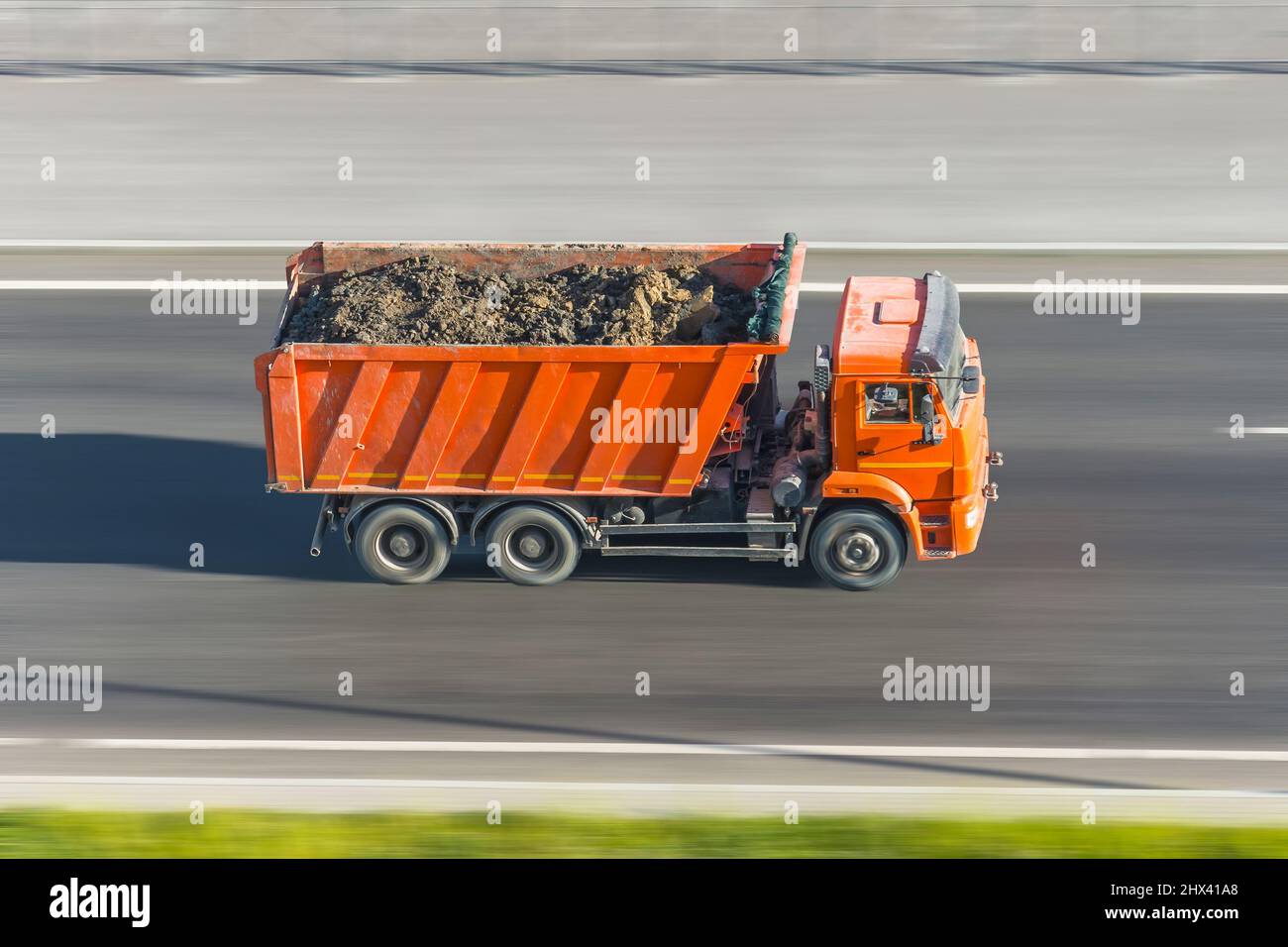 Truck dump with a load of soil in the body rides at high speed on the ...