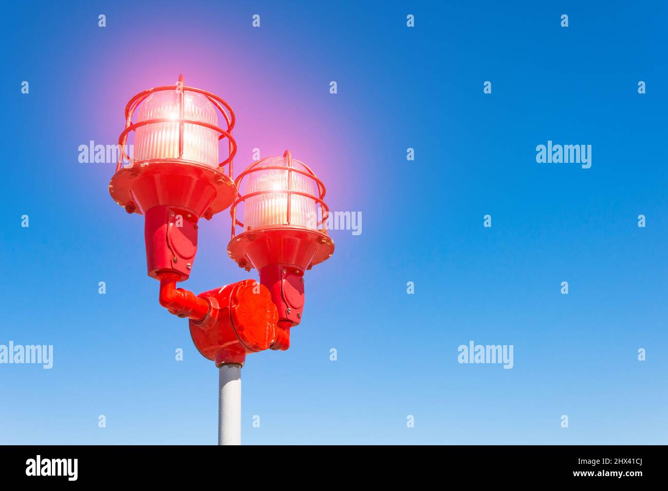 Red warning warning light with the light on, against the blue sky ...