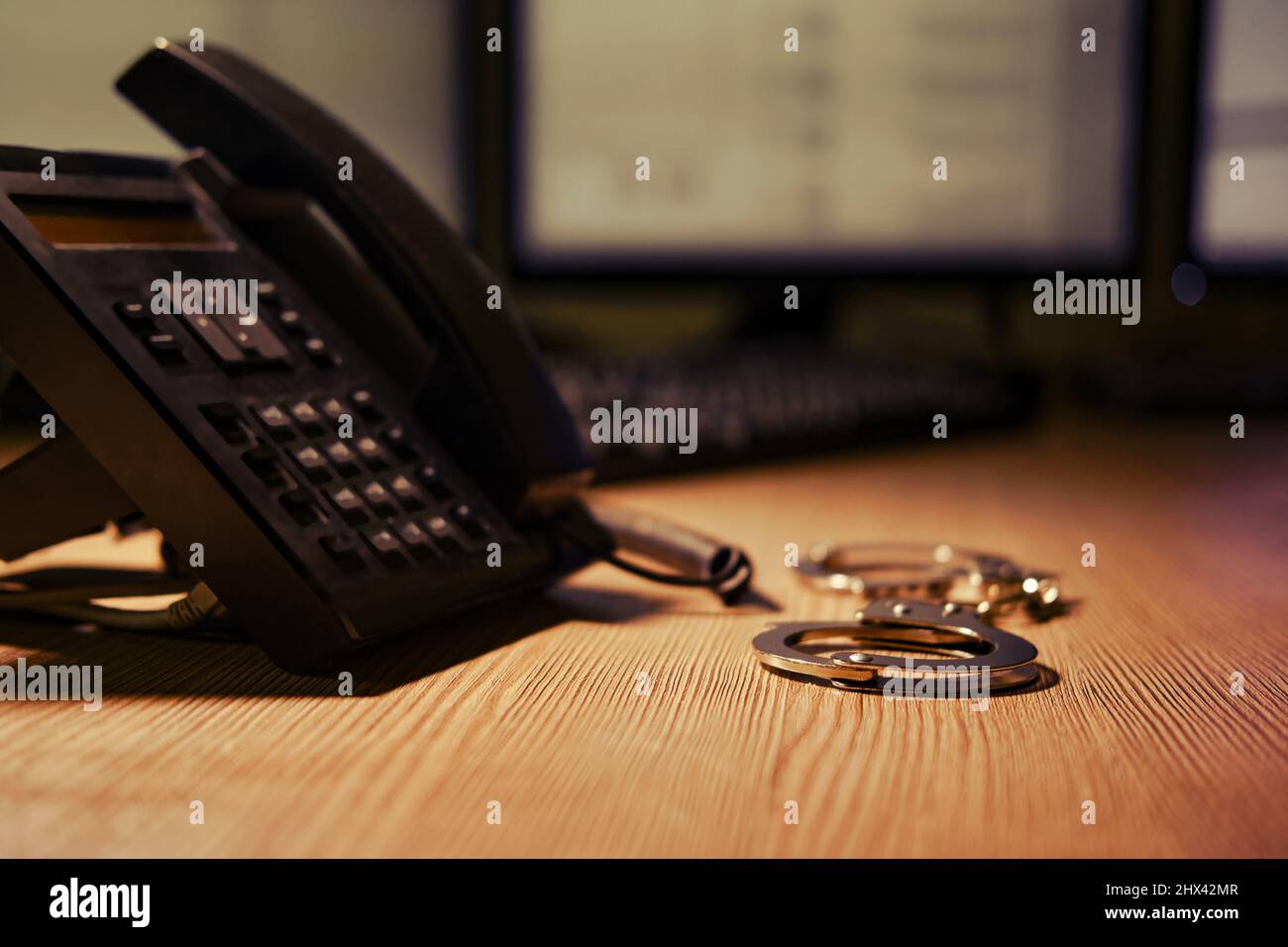 Landline phone and handcuffs on the table, close-up. Office desk in a ...