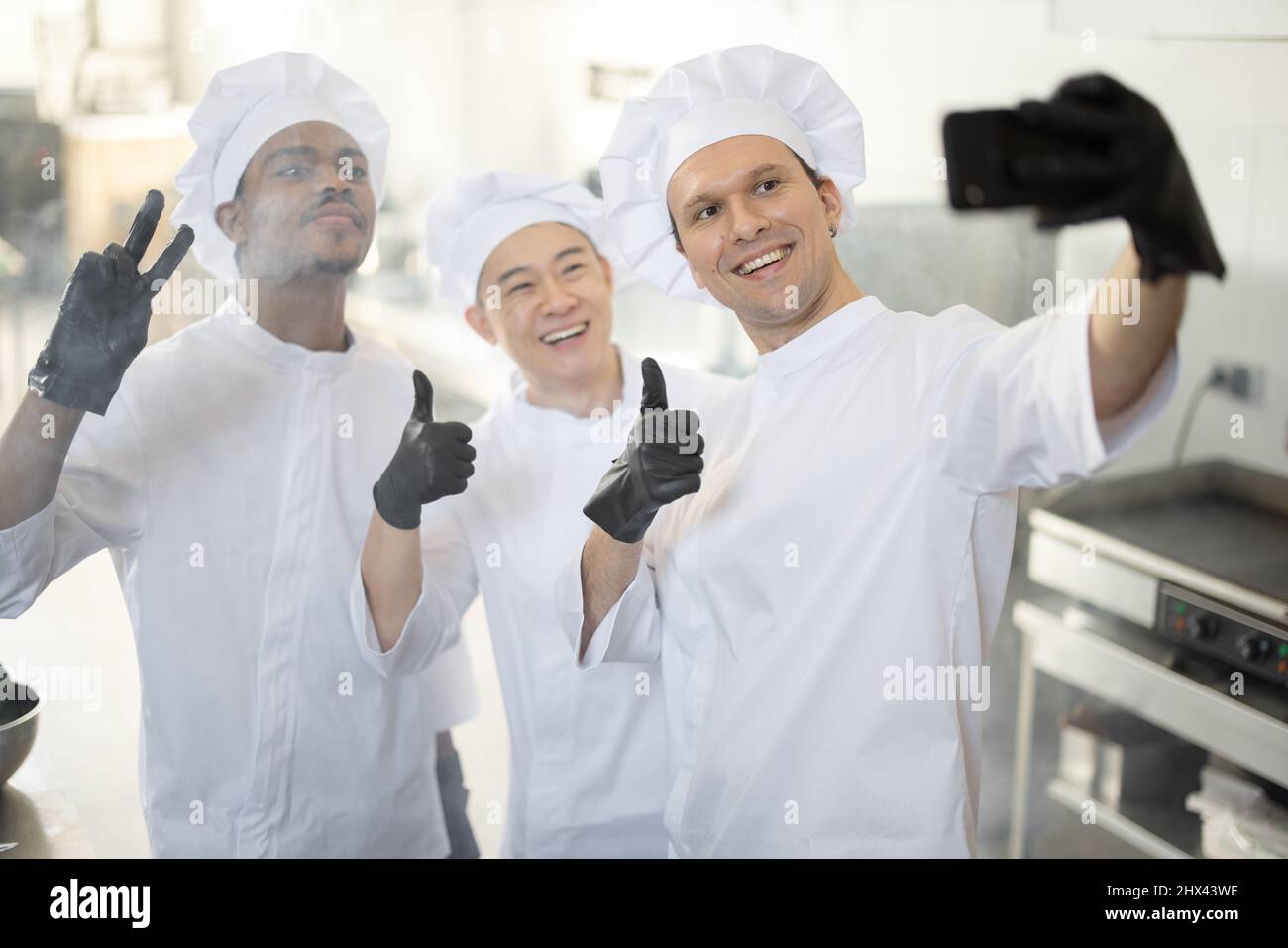 Happy multiracial team of cooks take selfie photo on phone while ...