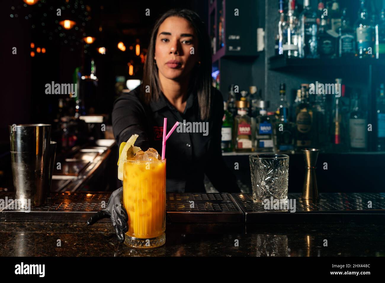 The young brunette Latina prepares a cocktail at the bar counter. job ...