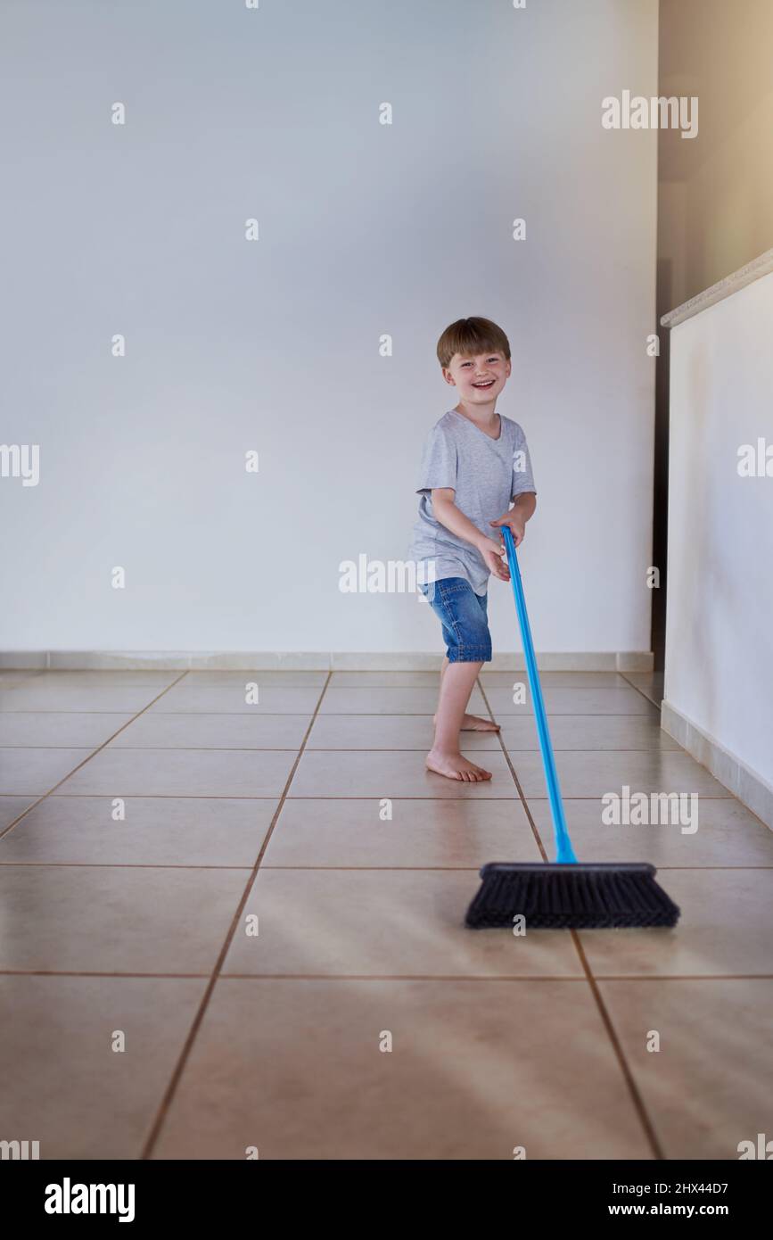 Sweeping is my chore for the day. Portrait of an adorable little boy ...