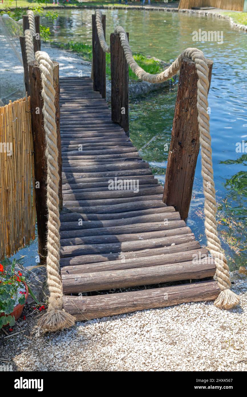 Wooden Logs Bridge With Rope Over Small Pond Stock Photo - Alamy