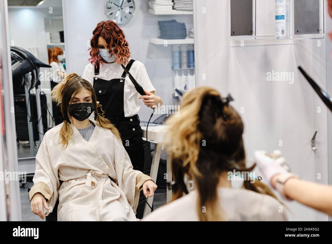 Young woman with face mask getting a new hairstyle by a professional ...