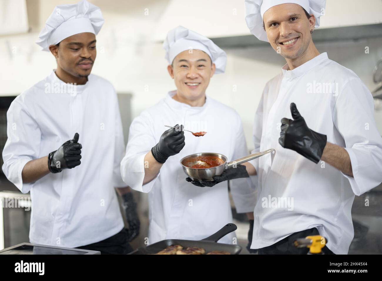 Portrait of three chef cooks with different ethnicities holding pan ...