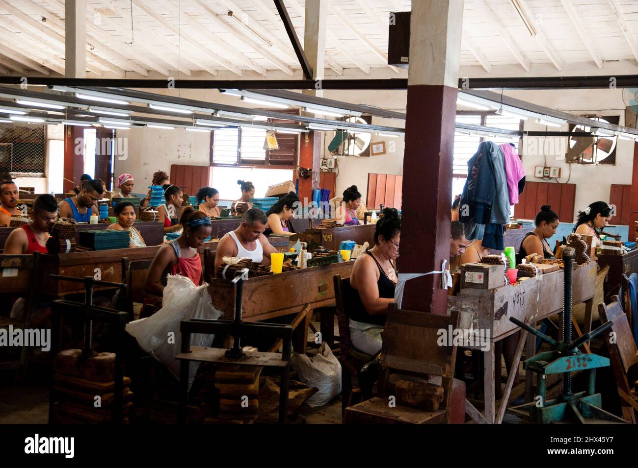 Men and woman sitting in a factory in Trinidad, Cuba working by hand on ...