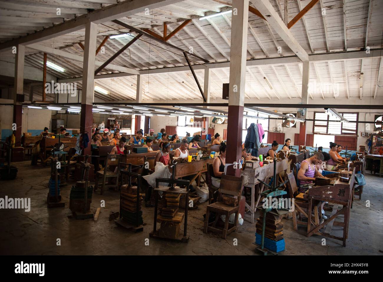 Men and woman sitting in a factory in Trinidad, Cuba working by hand on ...
