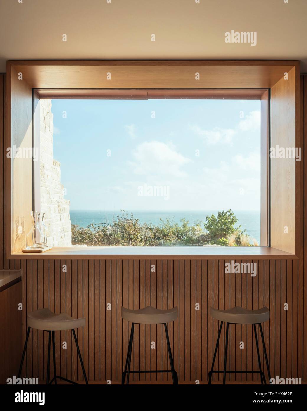 Interior view looking out of a picture window with breakfast bar stools ...