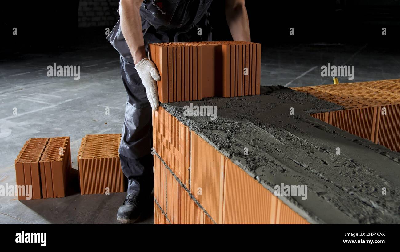 Industrial bricklayer worker placing bricks on cement while building ...