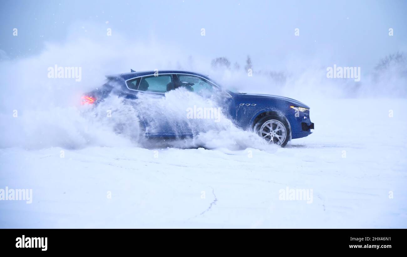 Winter driving. Blue car drives by icy track on snow covered lake at ...