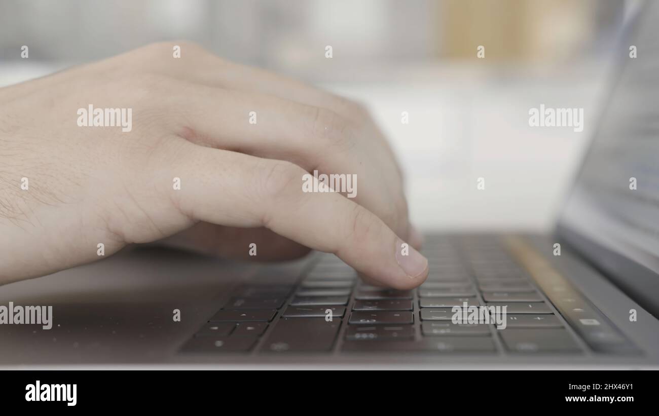 Working at home with laptop, male hands on the keyboard. Close up side ...