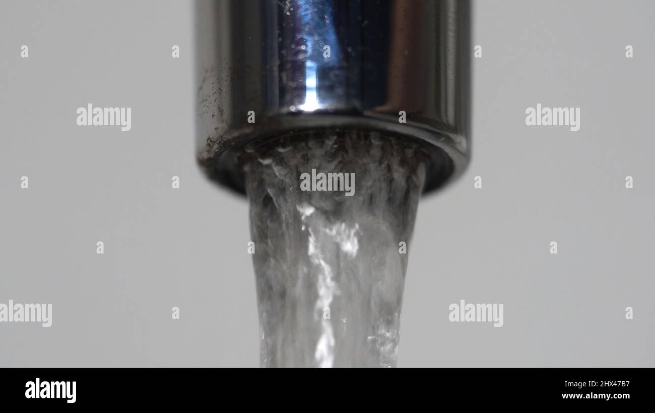 Extreme close up of the water flowing from the faucet. Chrome water tap ...