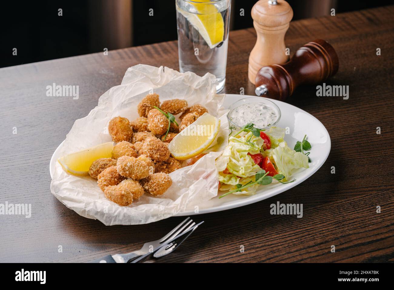 Fried crispy mussels in batter with lemon, sauce and salad Stock Photo ...