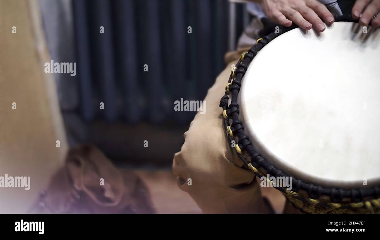 Close up of hands of a black man playing a drum. Drummer plays on small ...