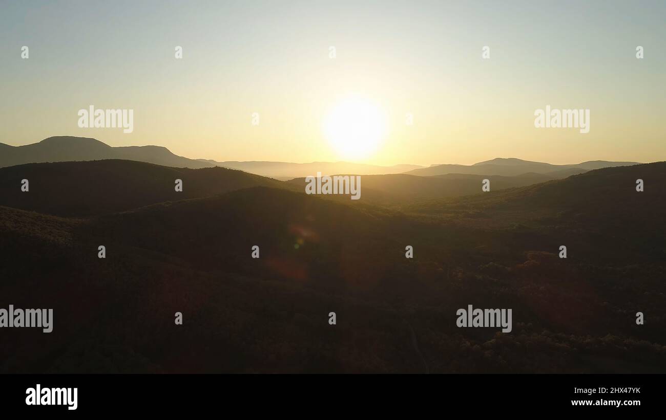 Aerial view of beautiful huge green mountains under the sunset sky ...