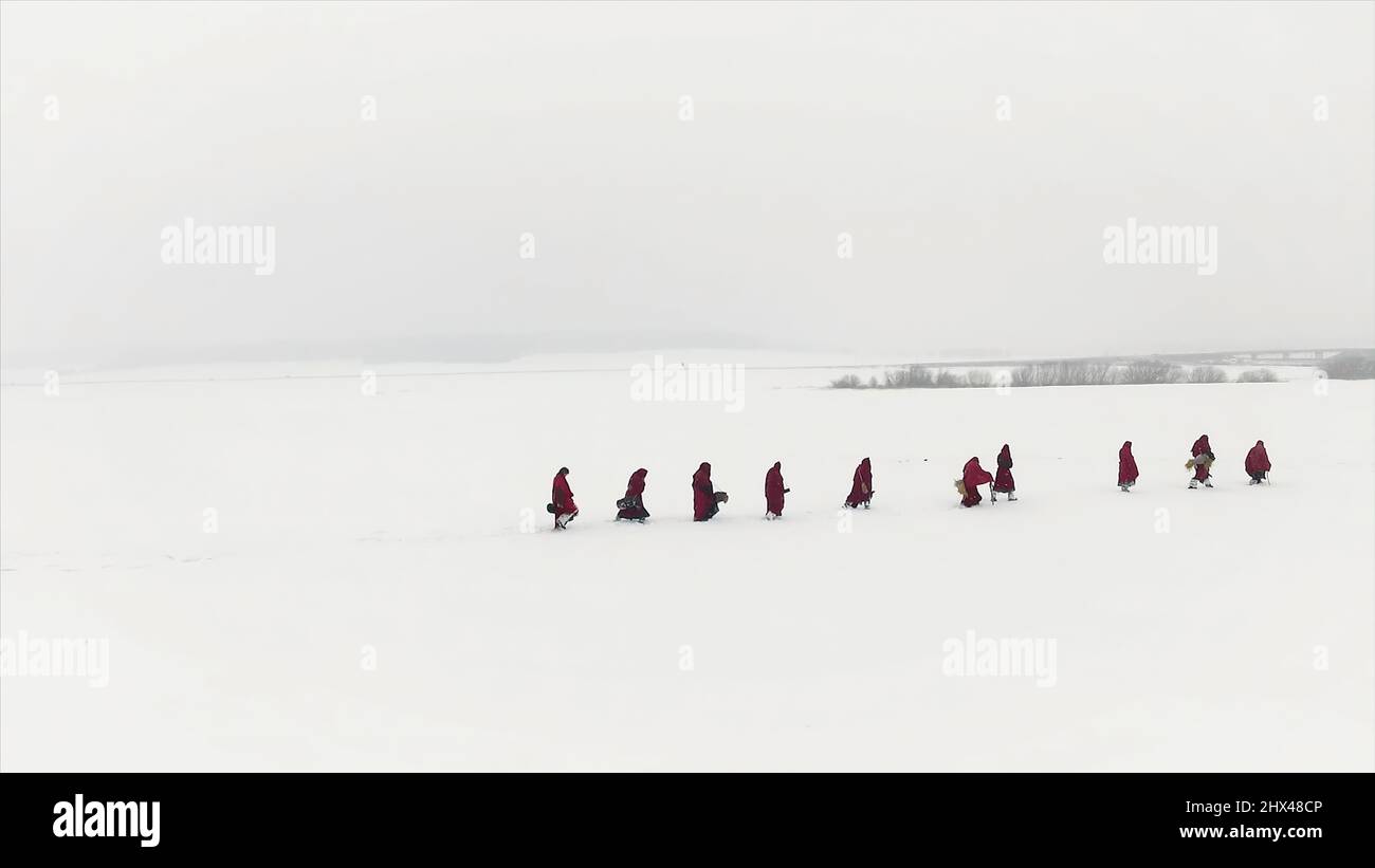 A group of people traveling on the taiga or snow-covered forest follow ...