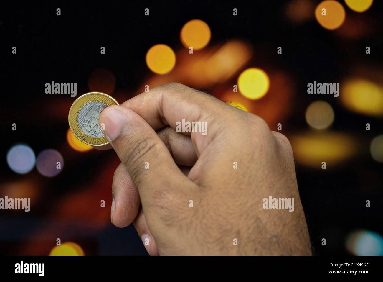 Holding a Brazilian money coin at a blurry lights background Stock ...
