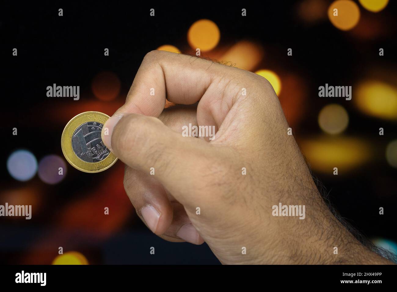 Holding a Brazilian money coin at a blurry lights background Stock ...
