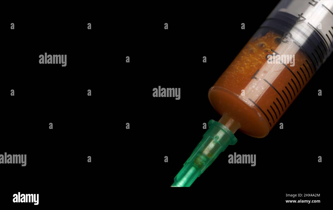 Syringe with blood on a black background close up. The syringe with the ...