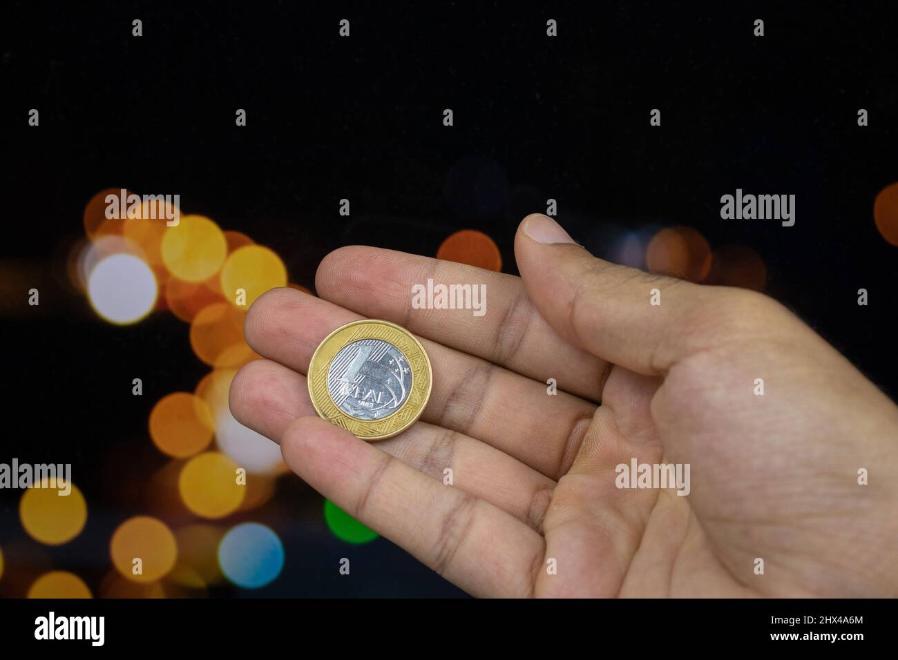 Holding a Brazilian money coin at a blurry lights background Stock ...