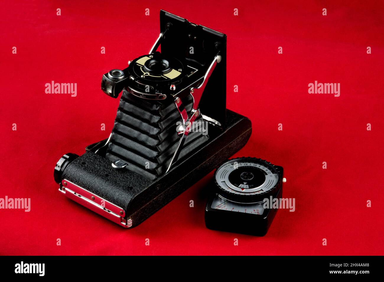 Old folding camera and exposure meter isolated on red Stock Photo - Alamy