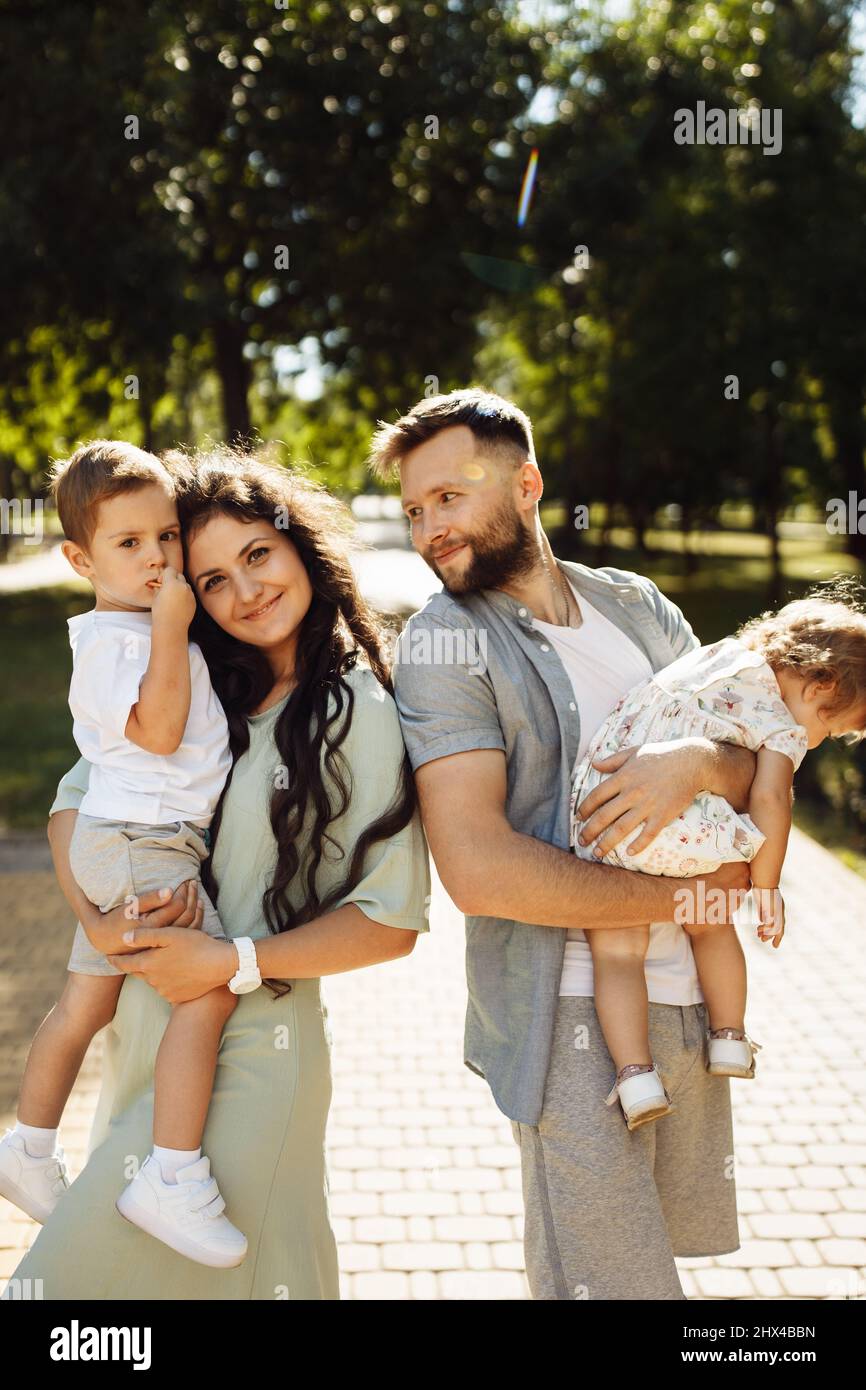 Overjoyed family with little kids at the park, caring dad hold in arms ...