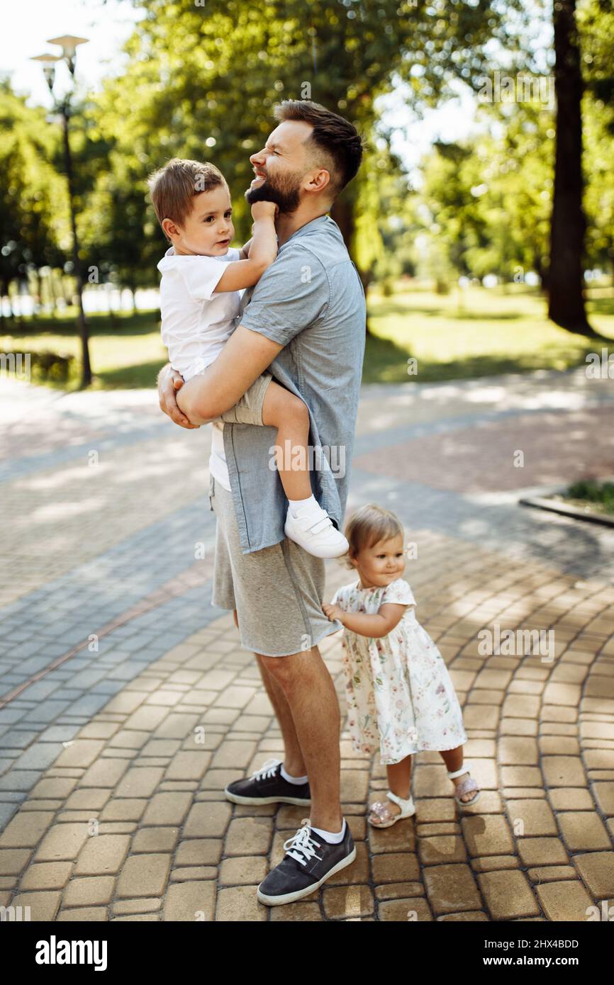 Caring dad with little kids at the park, lovely man hold in arms cute ...