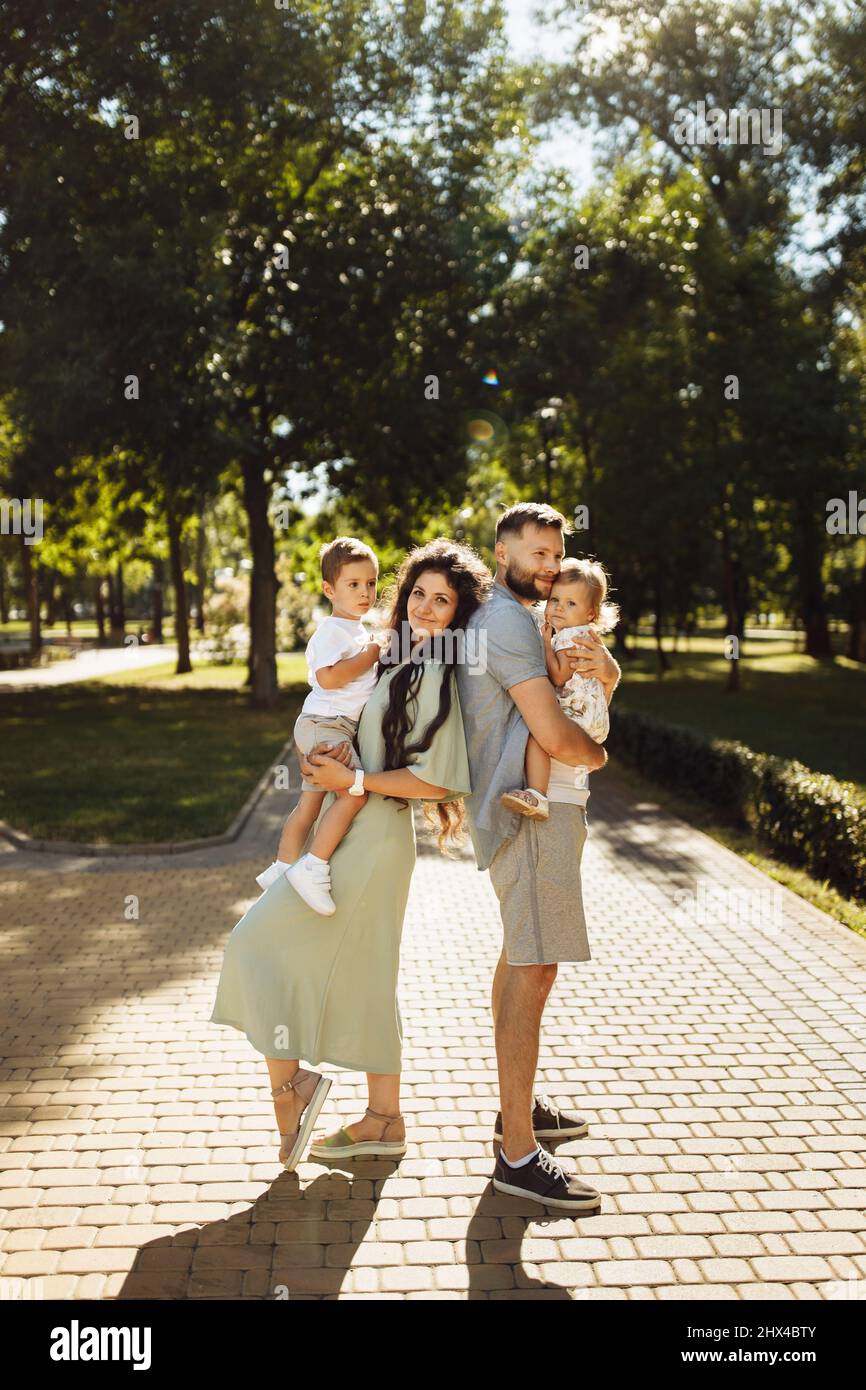 Overjoyed family with little kids at the park, caring dad hold in arms ...