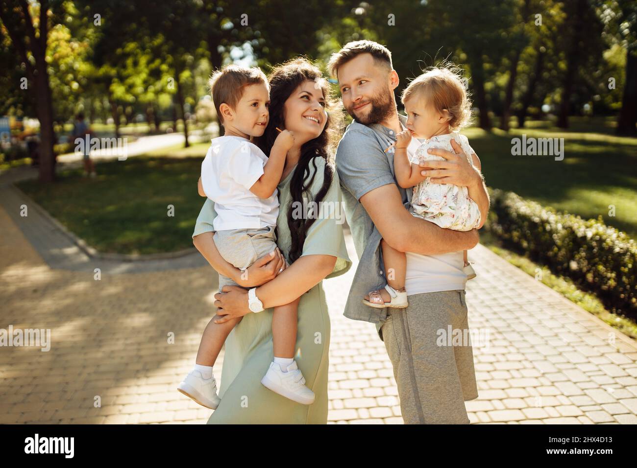 Overjoyed family with little kids at the park, caring dad hold in arms ...