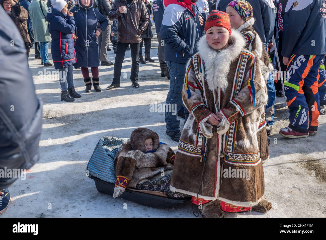 Young Nenet woman with a baby on a plastic sled at the Reindeer Herders ...