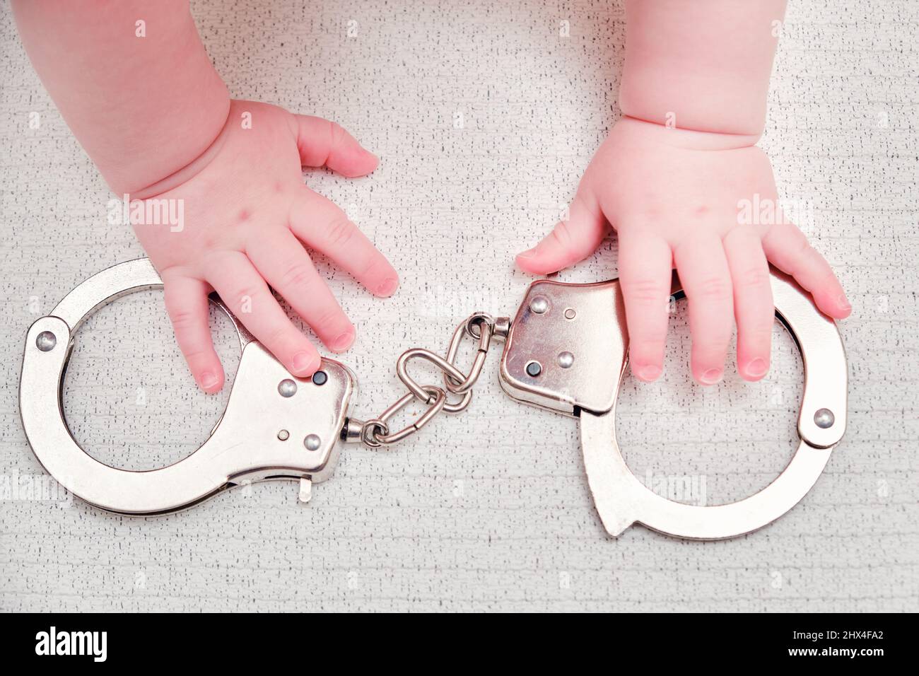 Baby hand and handcuffs, close-up. Children fingers and an object on a ...