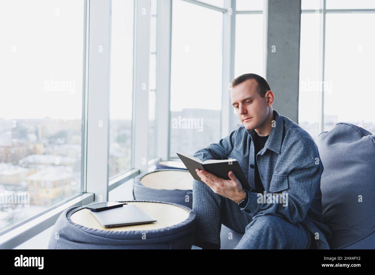 A male businessman in a casual suit resting in a comfortable pouf while ...