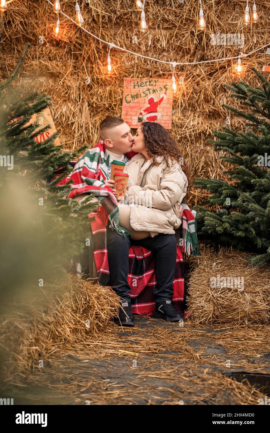 A beautiful young couple in white clothes are sitting near a Christmas ...