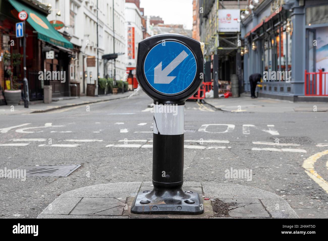 A keep left sign consisting of a white arrow pointing to the bottom ...