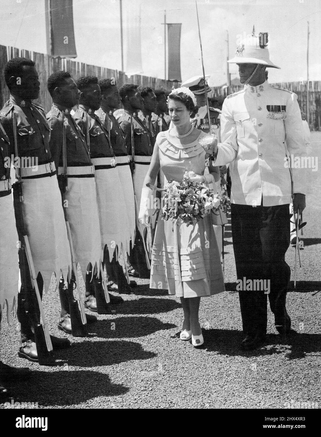 Eyes Front. Dwarfed by the tall officer of the guard the Queen inspects ...