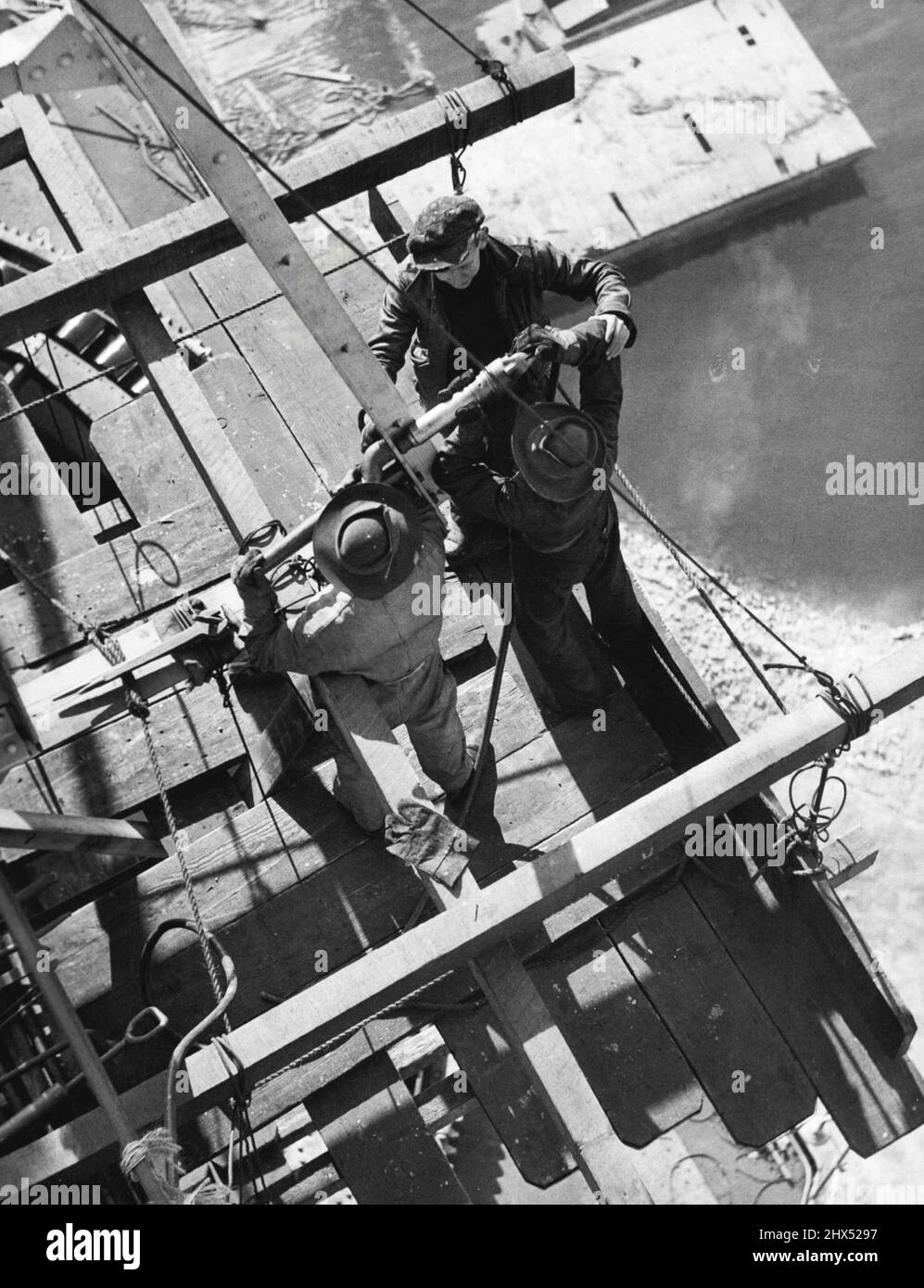 Riveting crew works on a temporary scaffold 200ft above water at Garden ...