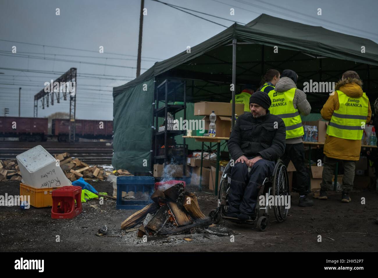 Medyka, Poland, March 9, 2022: a man in a wheel chair warms up over the ...