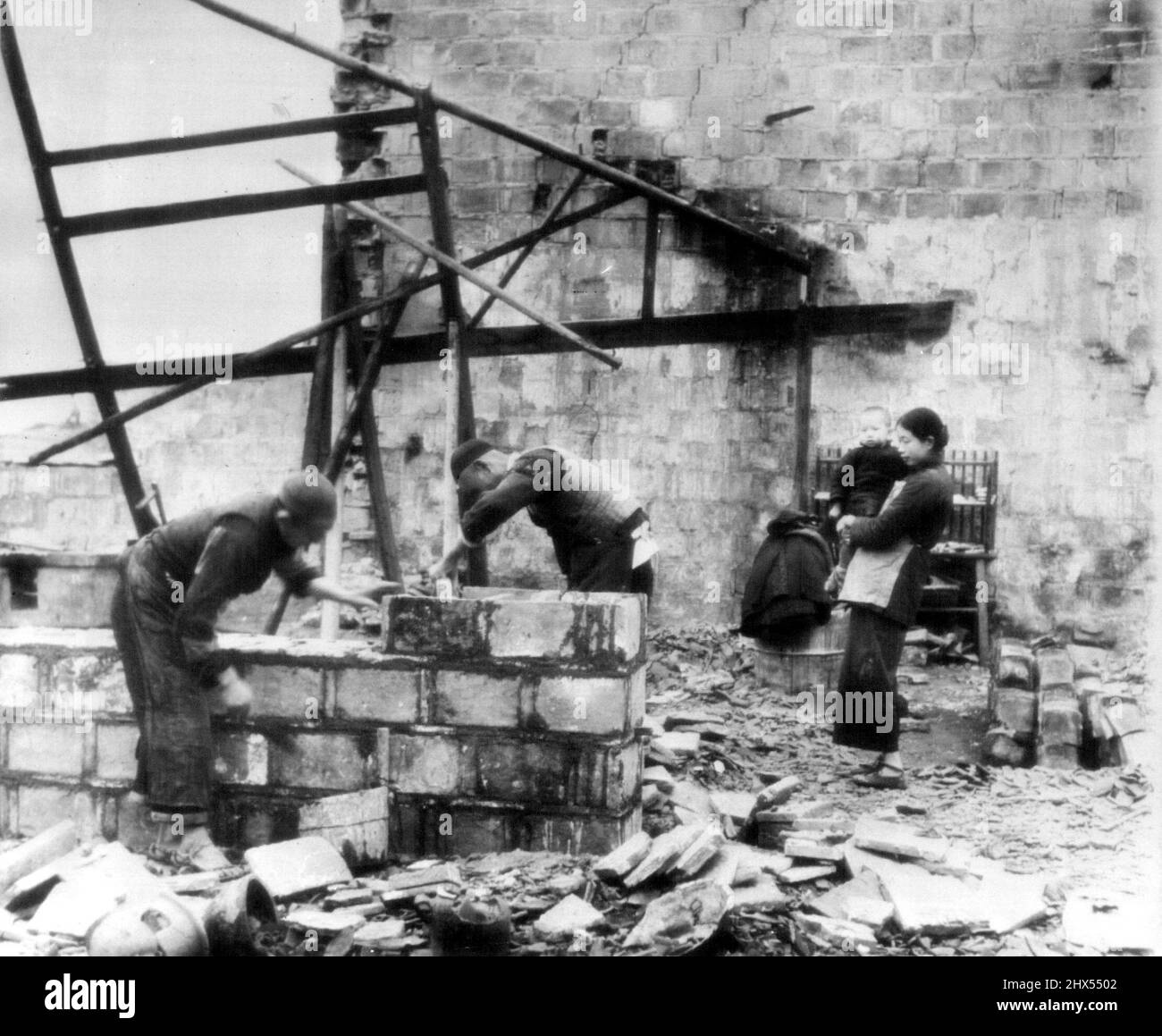 China Rebuilds -- A Chinese mother with a child in her arms watches men ...
