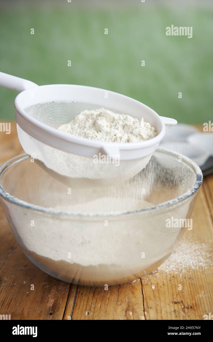 Seiving flour for herby muffins Stock Photo - Alamy