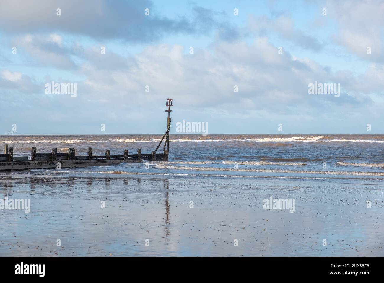 Wooden groynes and seaside breakers on the beach in Cromer on the North ...