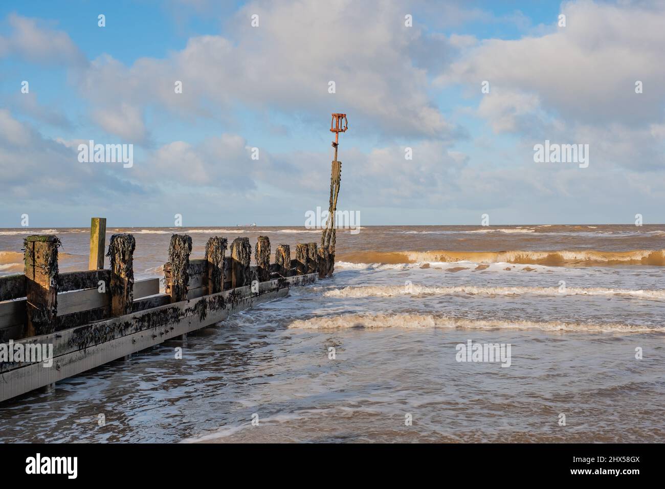 Wooden groynes and seaside breakers on the beach in Cromer on the North ...
