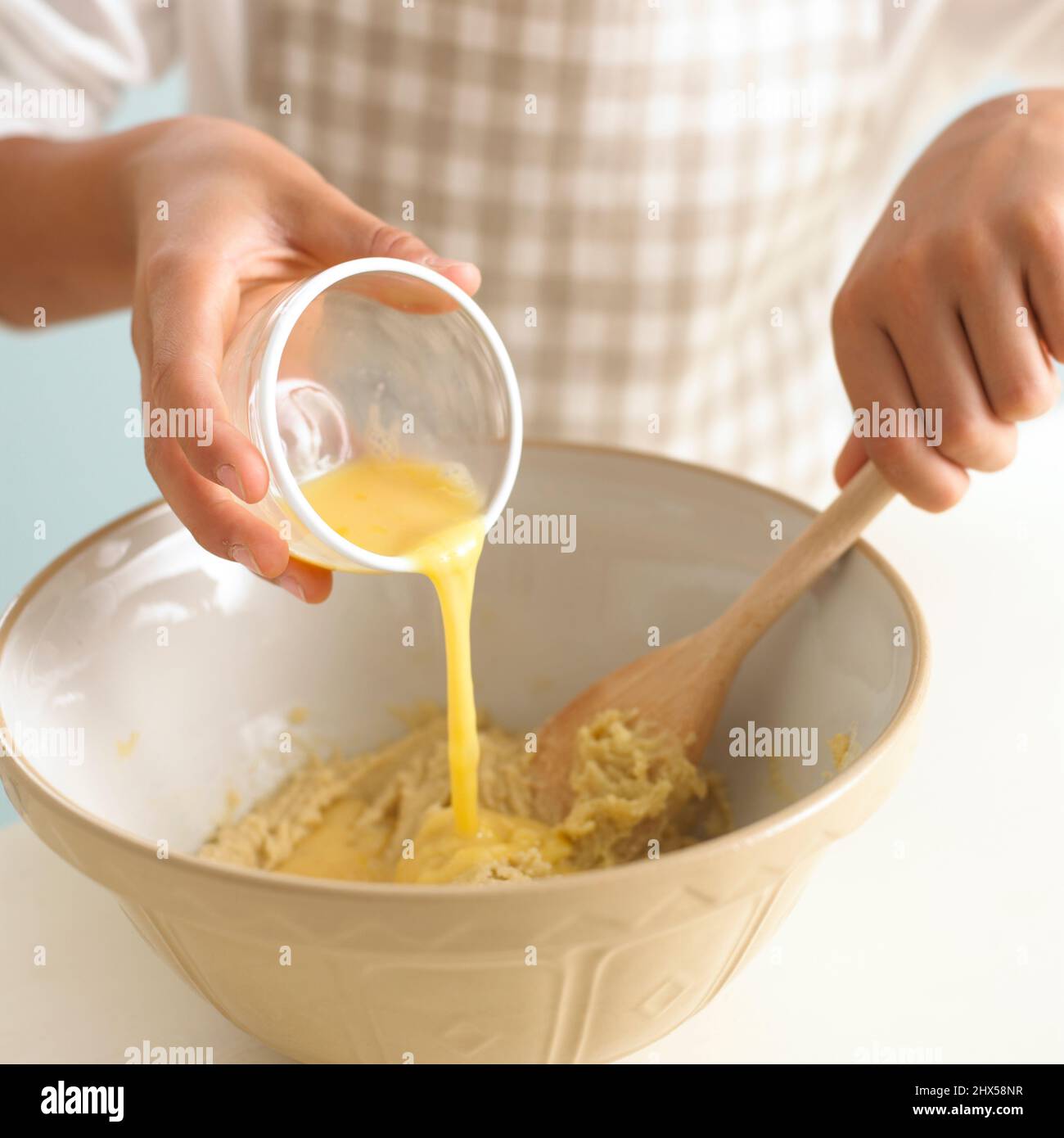 Adding egg yoke from small bowl onto ingredients in large mixing bowl ...