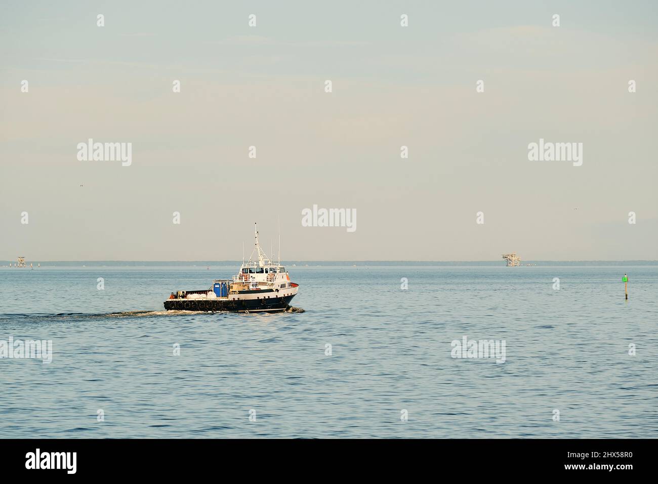 Oil rig tender or supply ship moving toward a distant oil rig in the ...