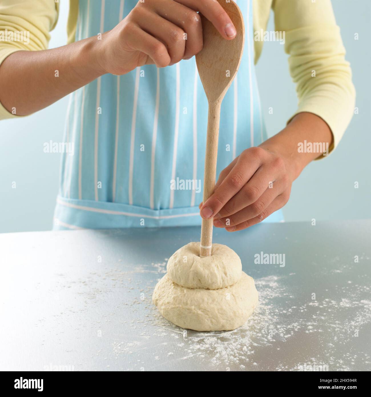 Boy making whole in dough using wooden spoon Stock Photo - Alamy
