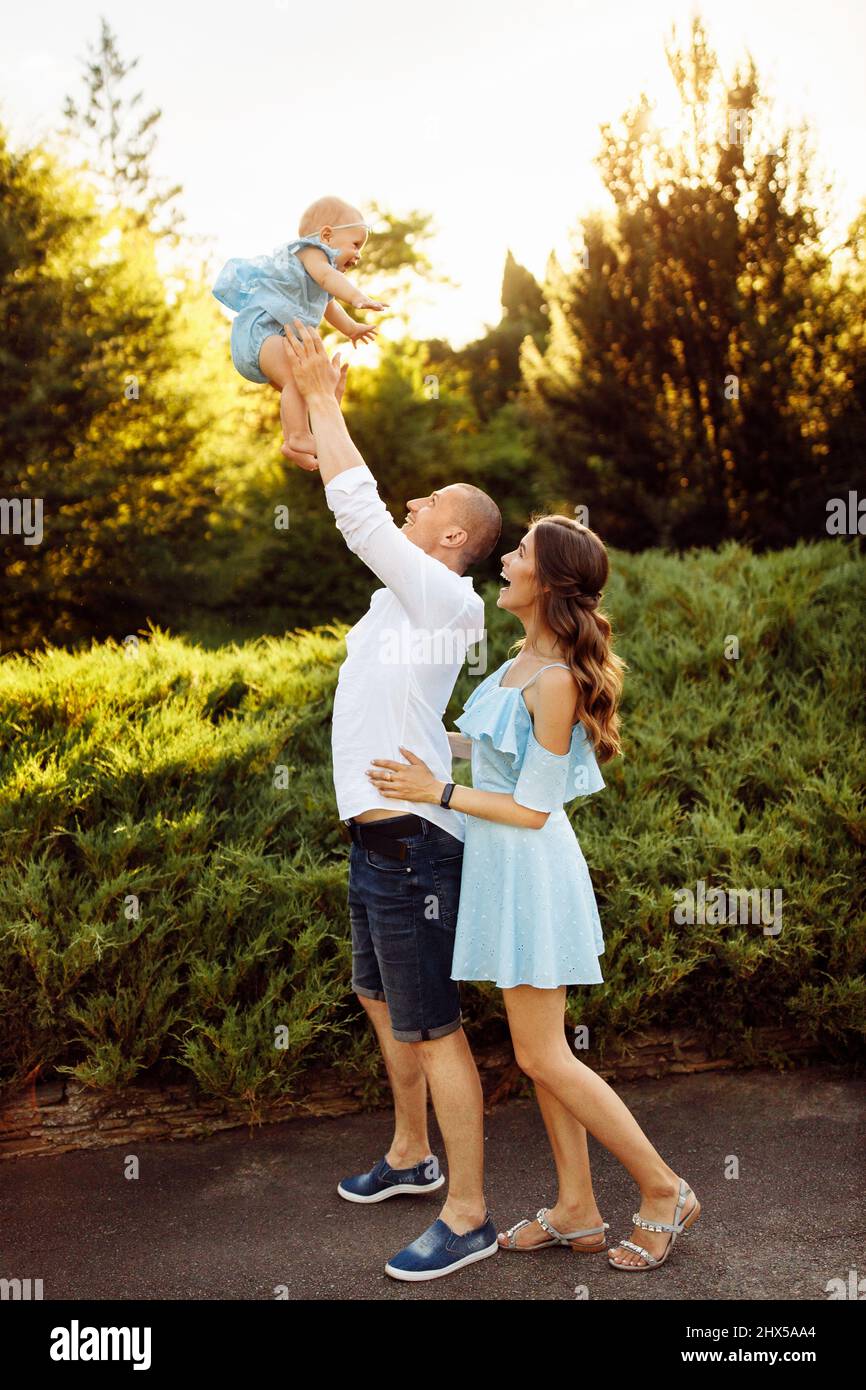 Happy loving family with cute baby girl at the park, strong dad lift in ...