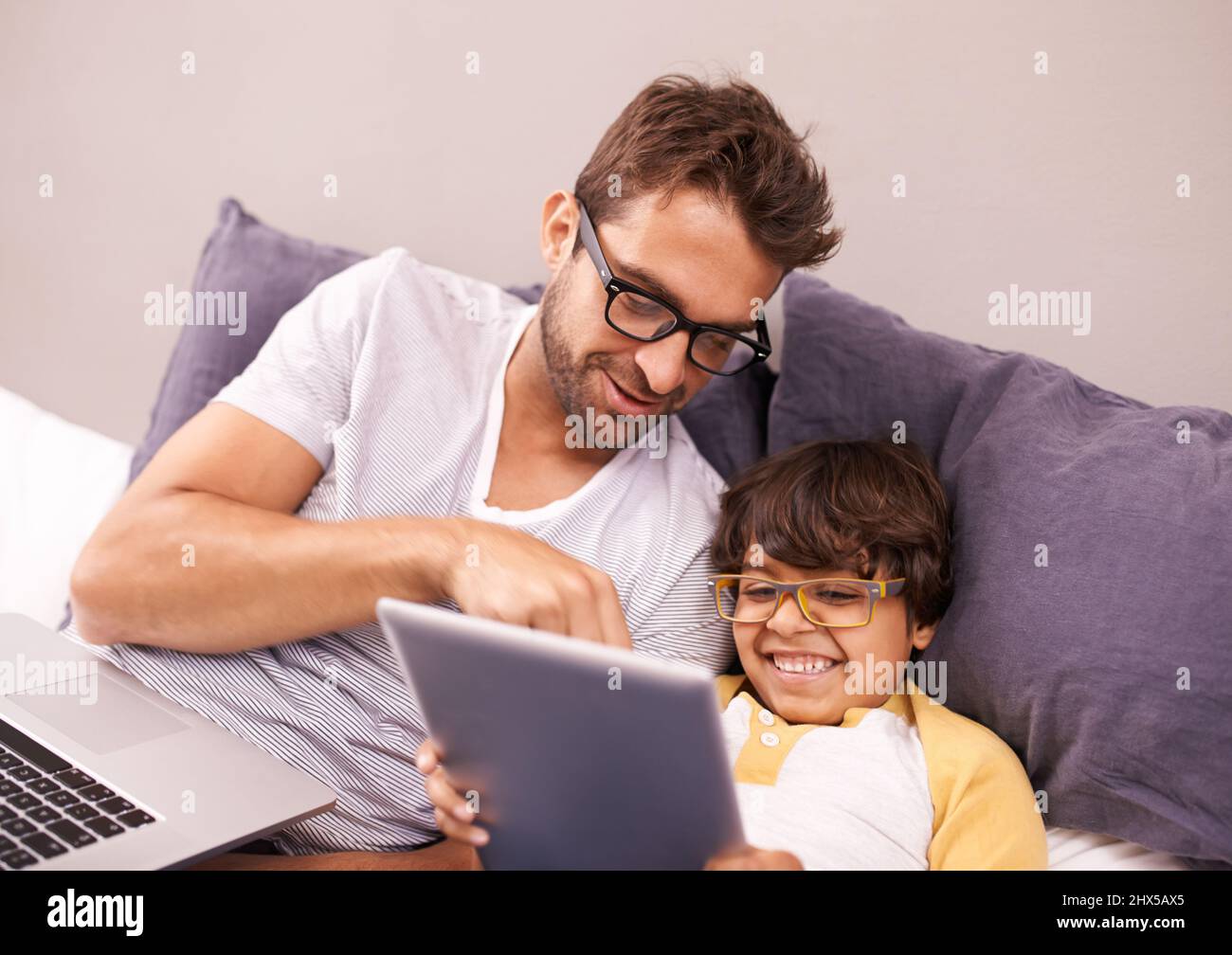 Thats my favorite. Father and son lying on bed while using a laptop and ...