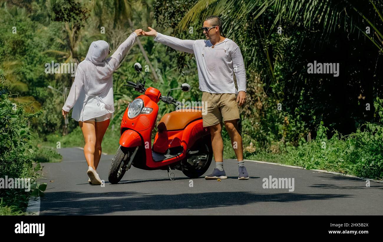 Two caucasian tourist woman man dance near scooter. Love couple on red ...