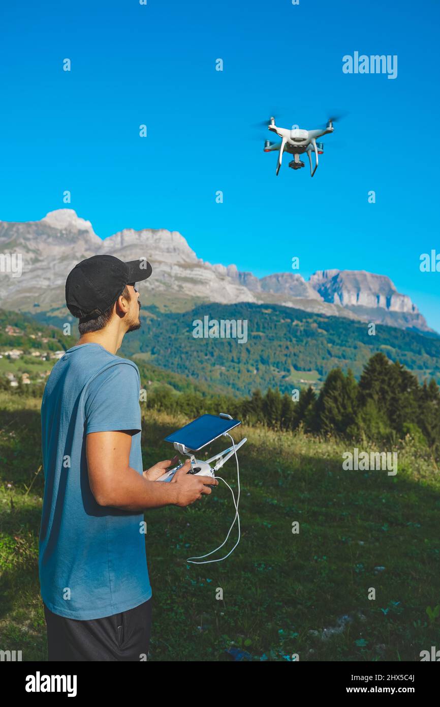 Young man flying drone on amazing mountain landscape. Man operating a ...